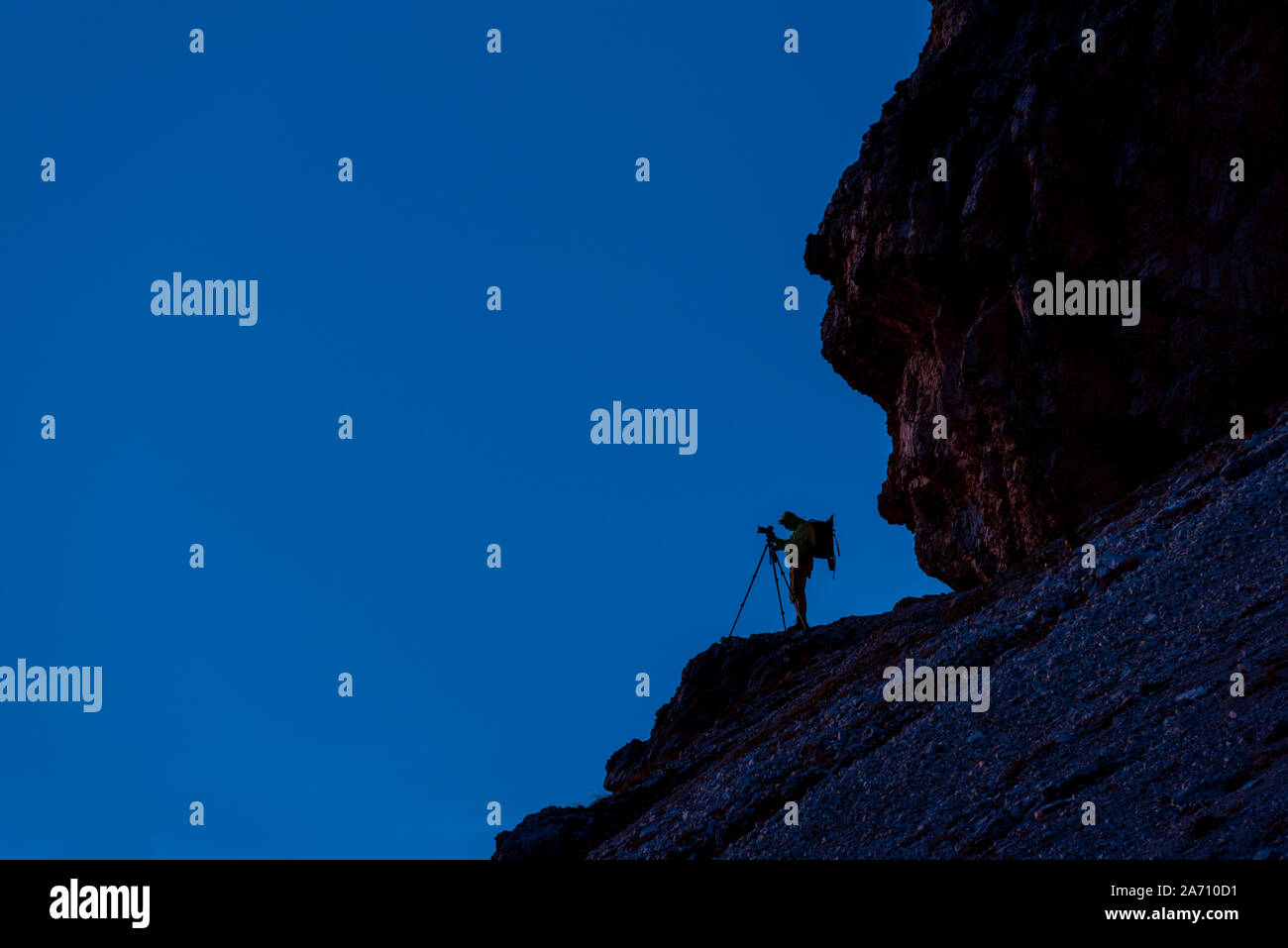 Landscape photographer in cliff face taking nature pictures of ...