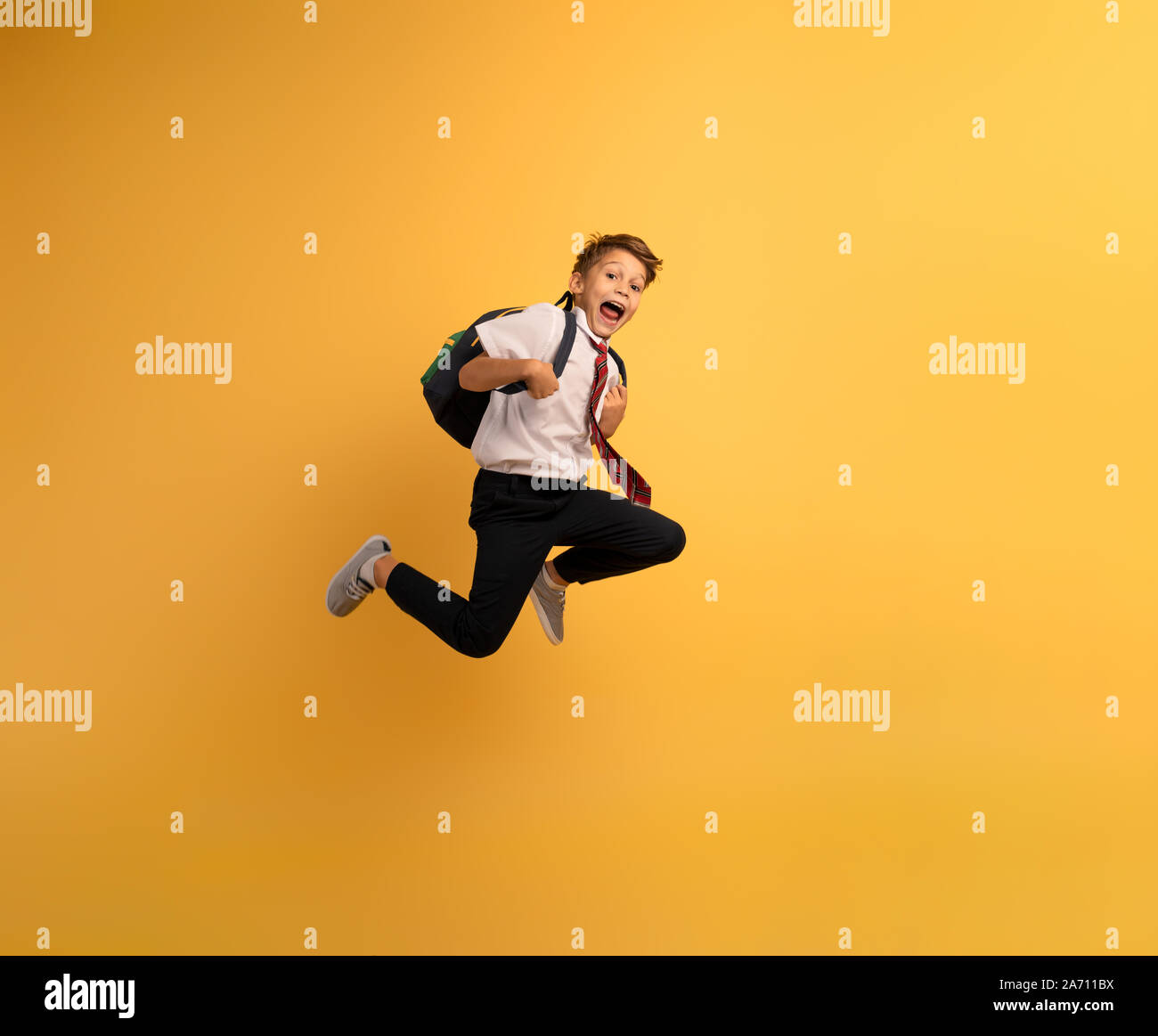 Young boy student runs fast to escape from school. Yellow background ...