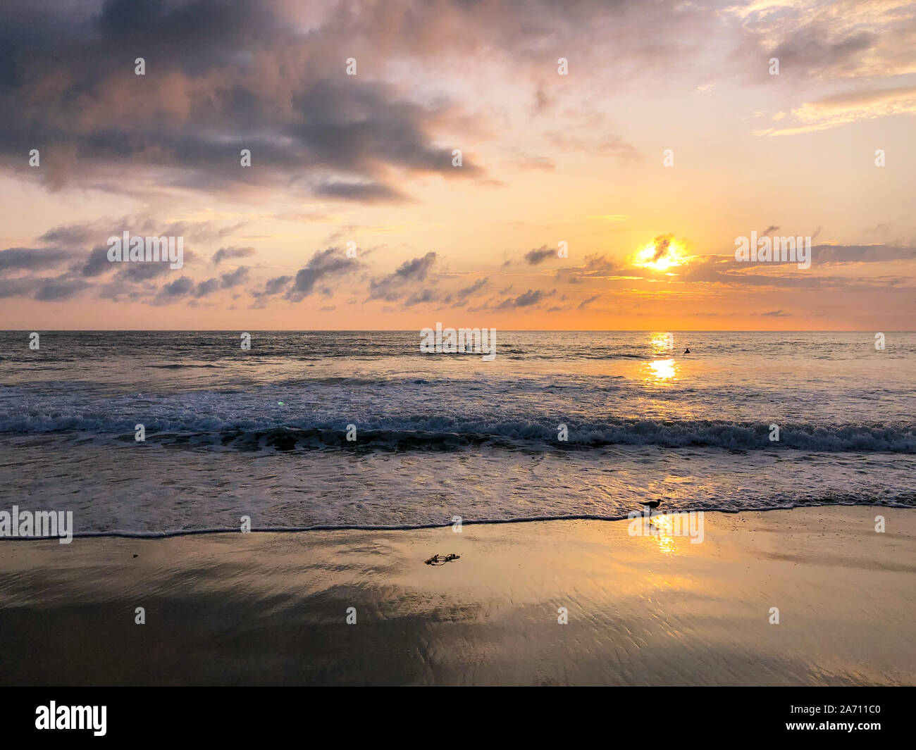 Colorful ocean beach sunset facing the sun with deep clouded sky ...