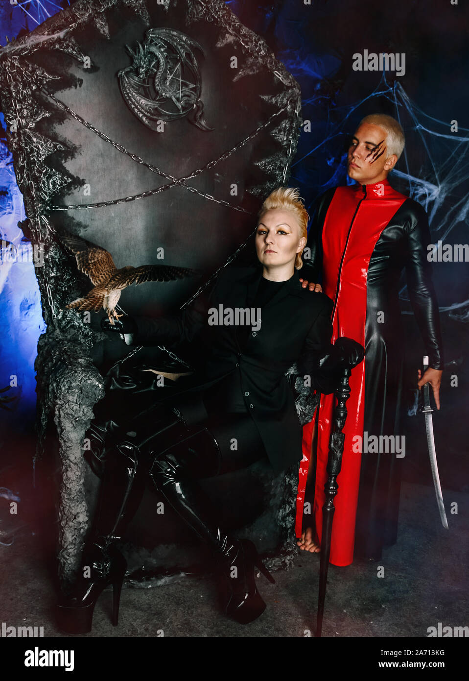 Gothic couple with little bird on a huge scary throne ready for ...