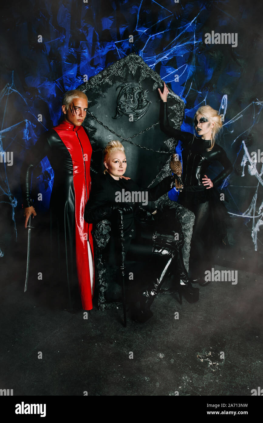 Gothic 3 friends in dark costumes with make up on a huge scary throne ...