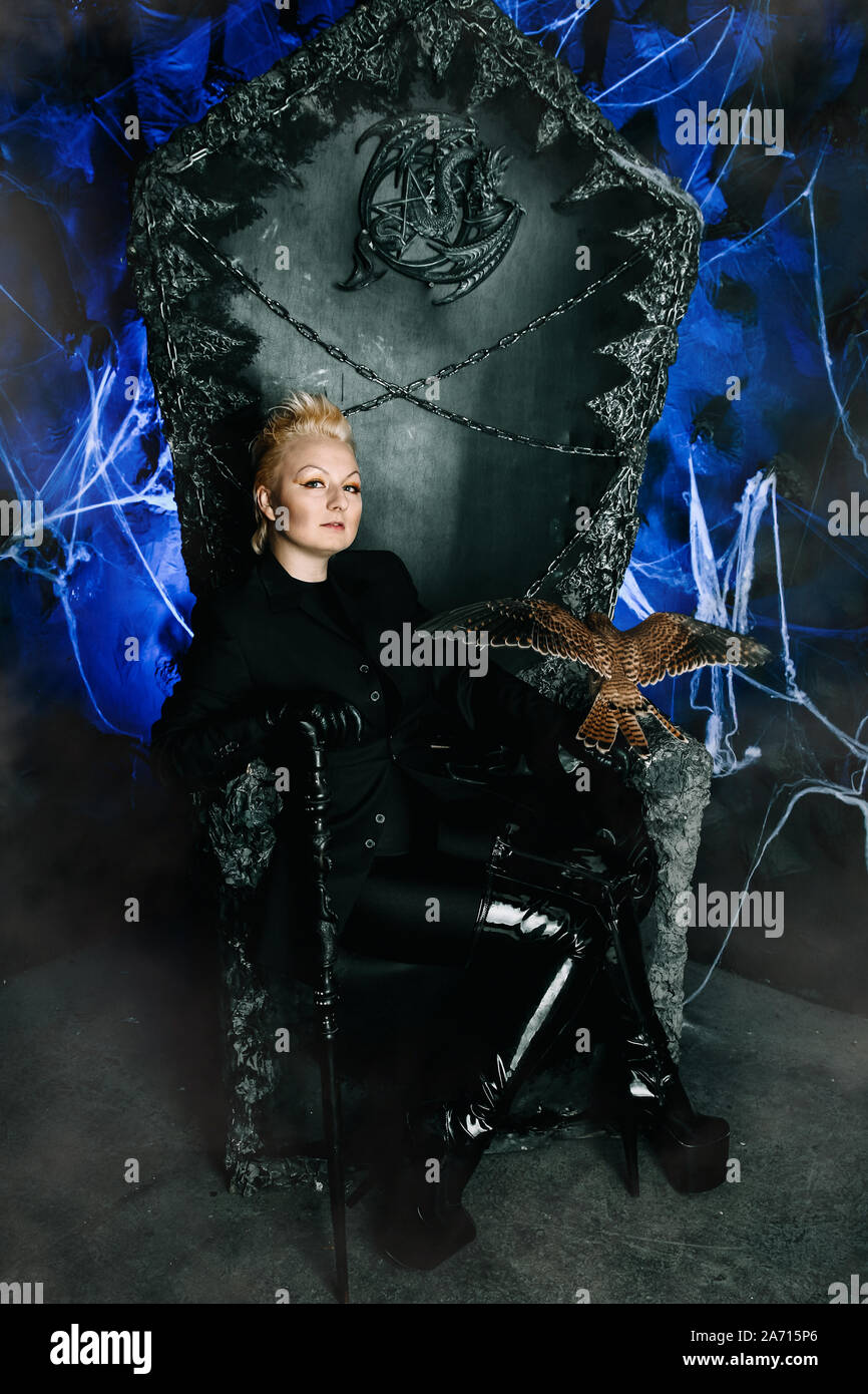 Gothic woman with bird on huge scary throne with blue spooky light ...