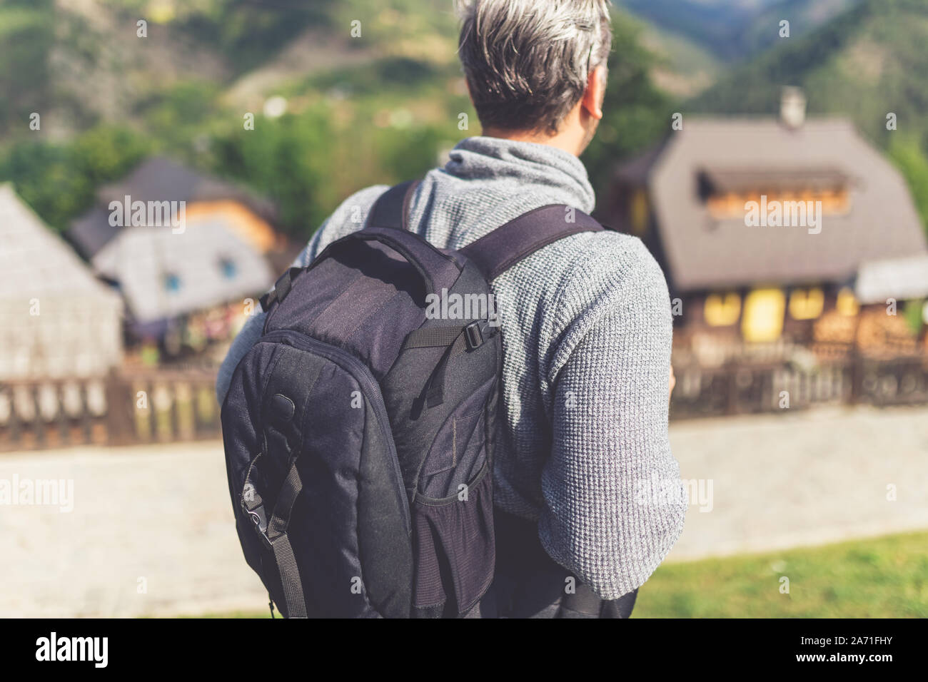 Man tourist with backpack arriving in mountain village Stock Photo - Alamy