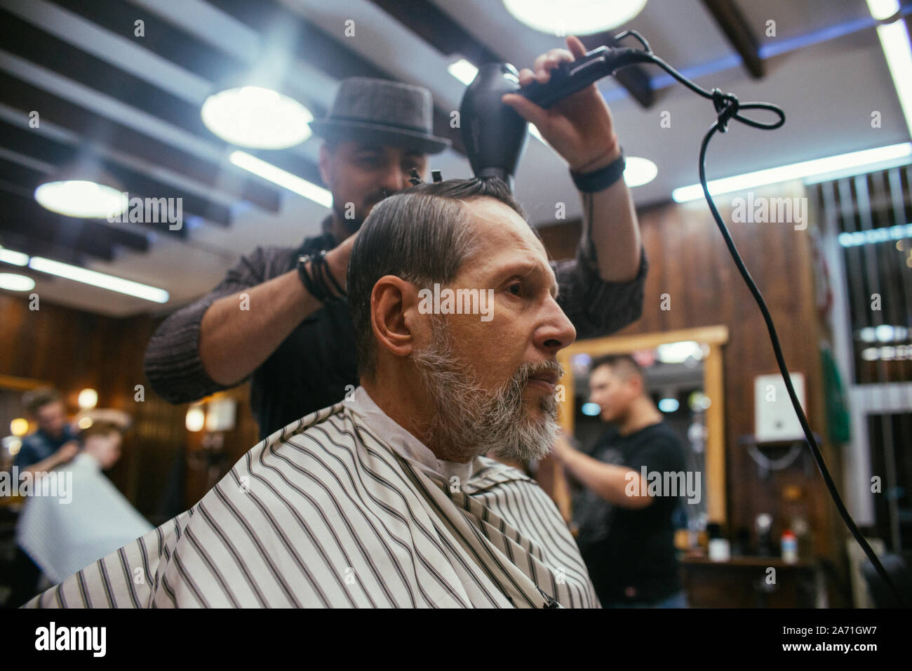 Grandpa gets a haircut at the hairdresser in Barber shop. Trendy ...