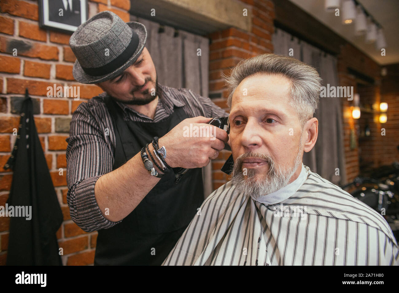 Grandpa gets a haircut at the hairdresser in Barber shop. Trendy ...