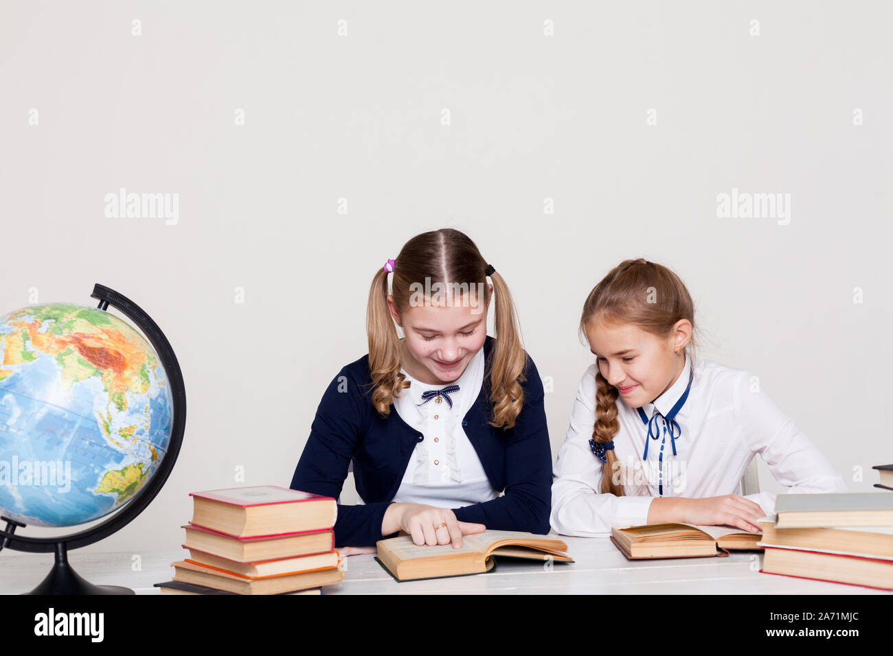 two schoolgirl girls with books at the school desk Stock Photo - Alamy