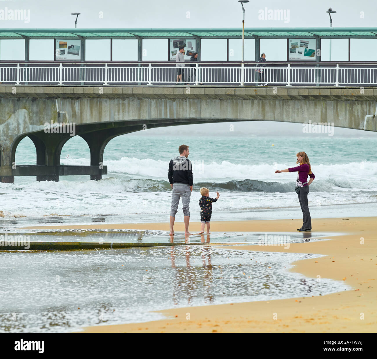 Family of mother, father and child on the shoreline under the pier of ...