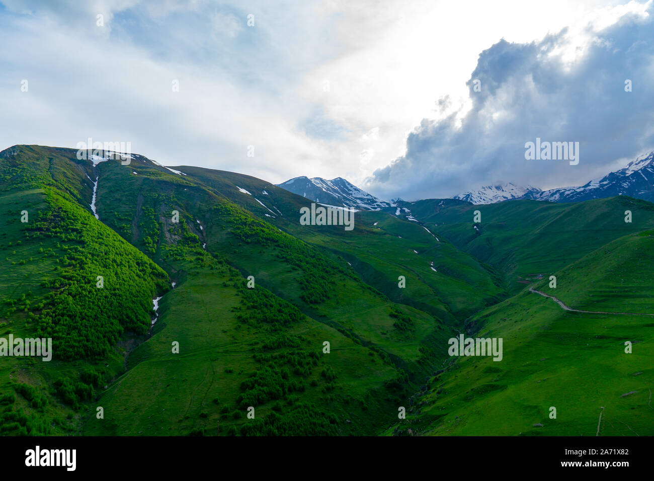 Landscape mountain view peaks in snow and green hills, deep blue sky ...