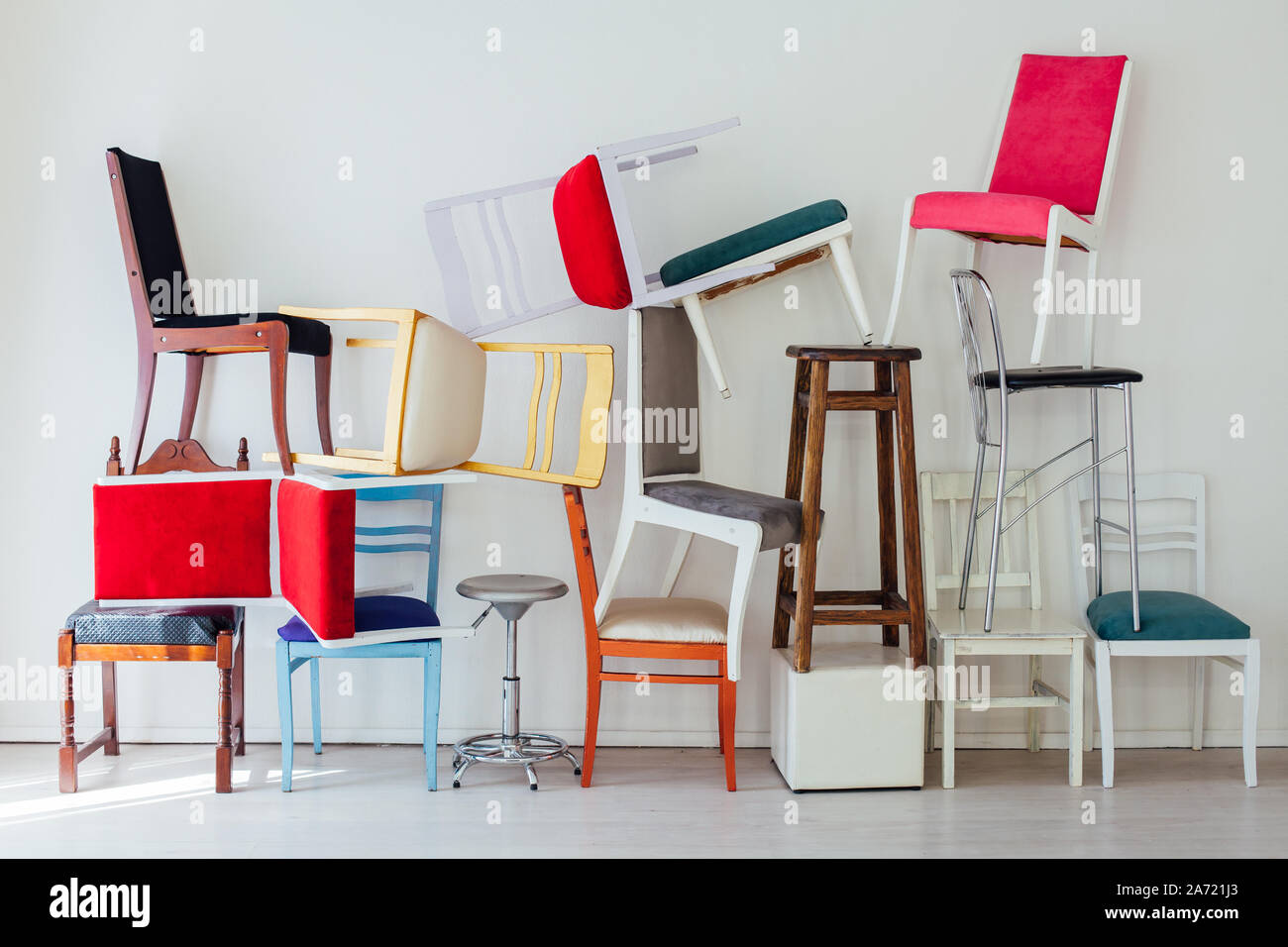 many multicolored chairs in the mess of the white room Stock Photo - Alamy