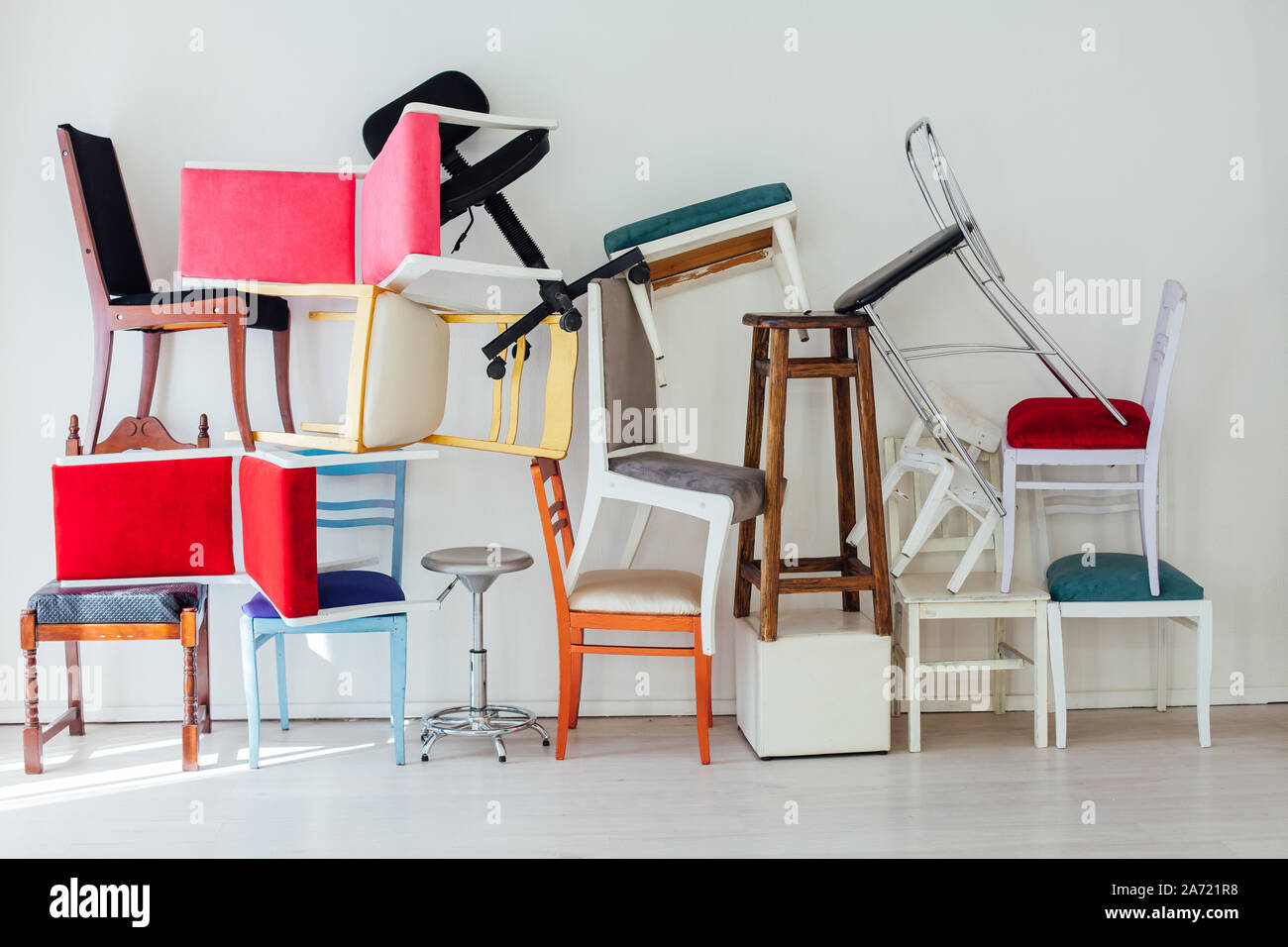 many multicolored chairs in the mess of the white room Stock Photo - Alamy