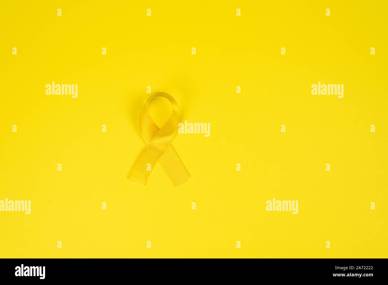 Yellow gold ribbon on a yellow background. Children cancer concept ...
