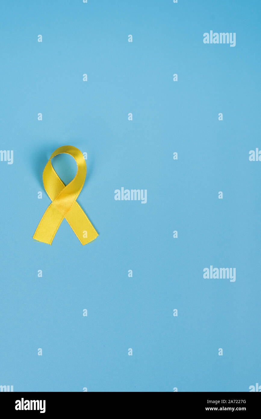 Yellow gold ribbon on a yellow background. Children cancer concept ...