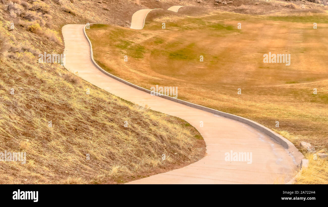 Panorama Winding narrow rural road through foothills and grass Stock ...