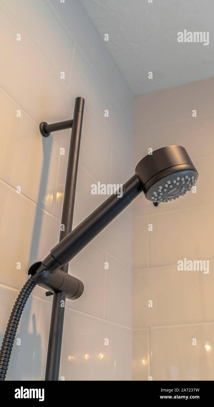 Vertical frame Shower head in a white tiled shower cubicle Stock Photo ...