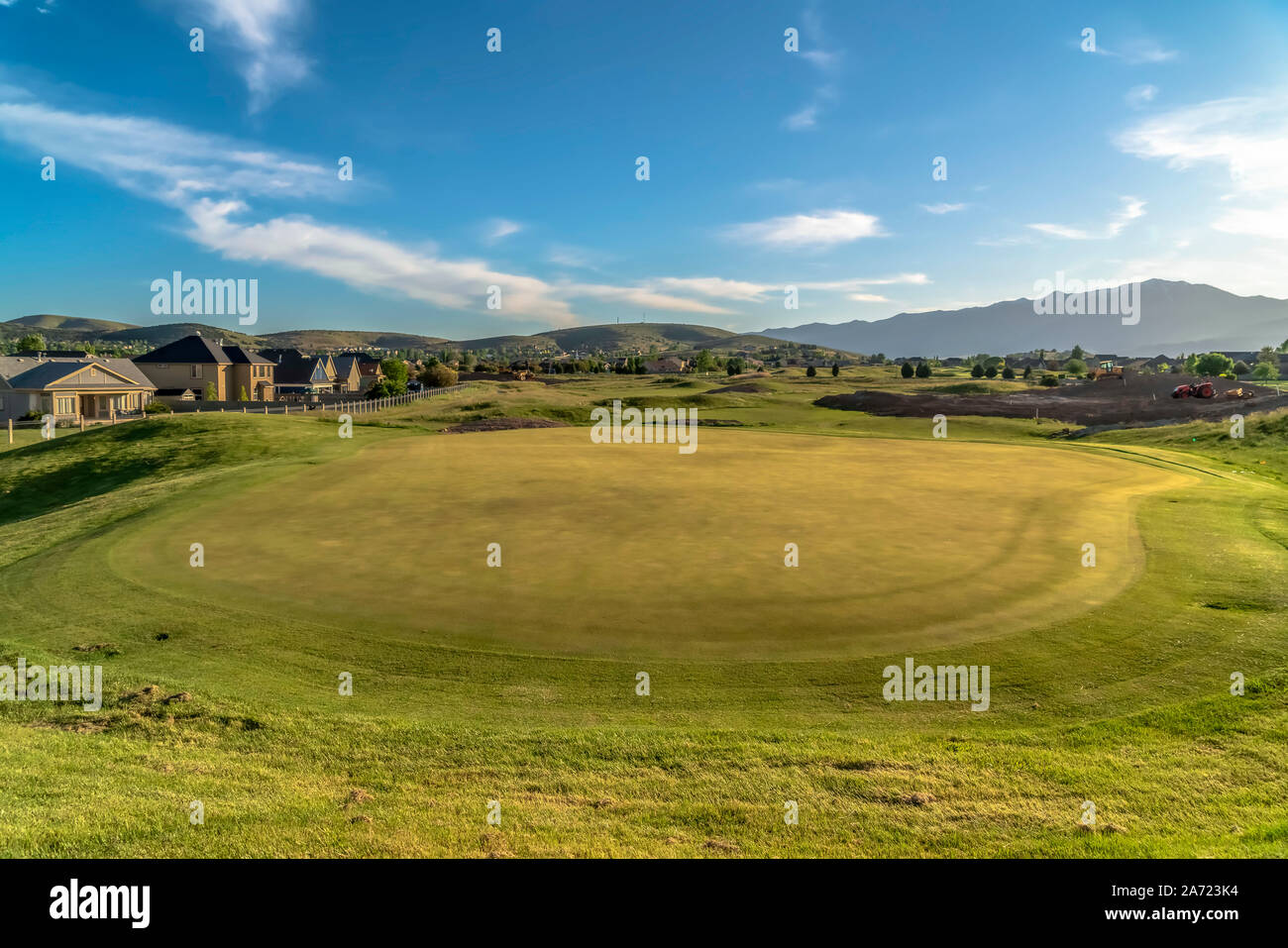 Scenic golf course landscape against houses and mountain under sky and ...