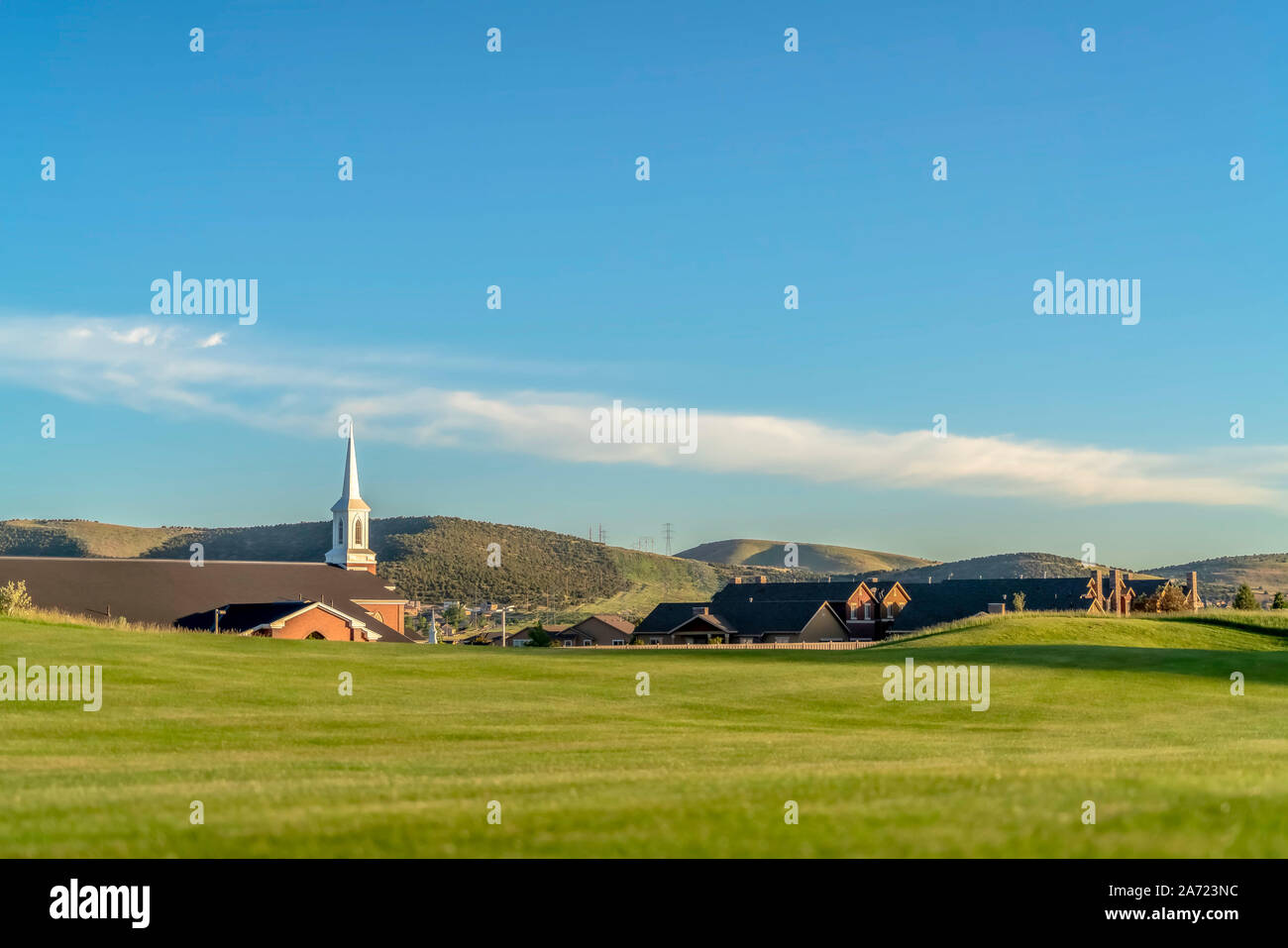 Golf course overlooking rooftops church steeple and mountain on a sunny ...