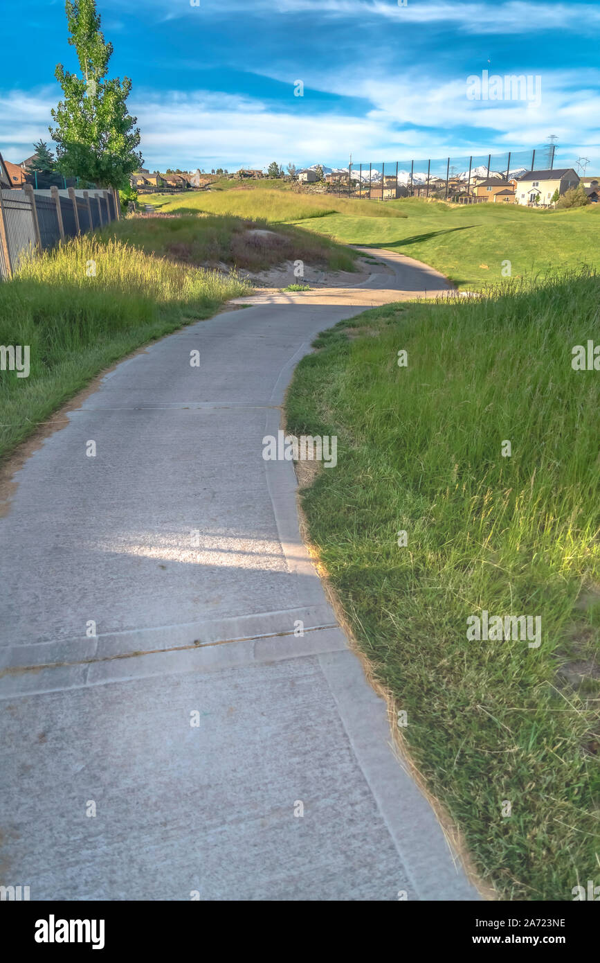 Pathway amid grasses leading to a golf course with houses in the ...