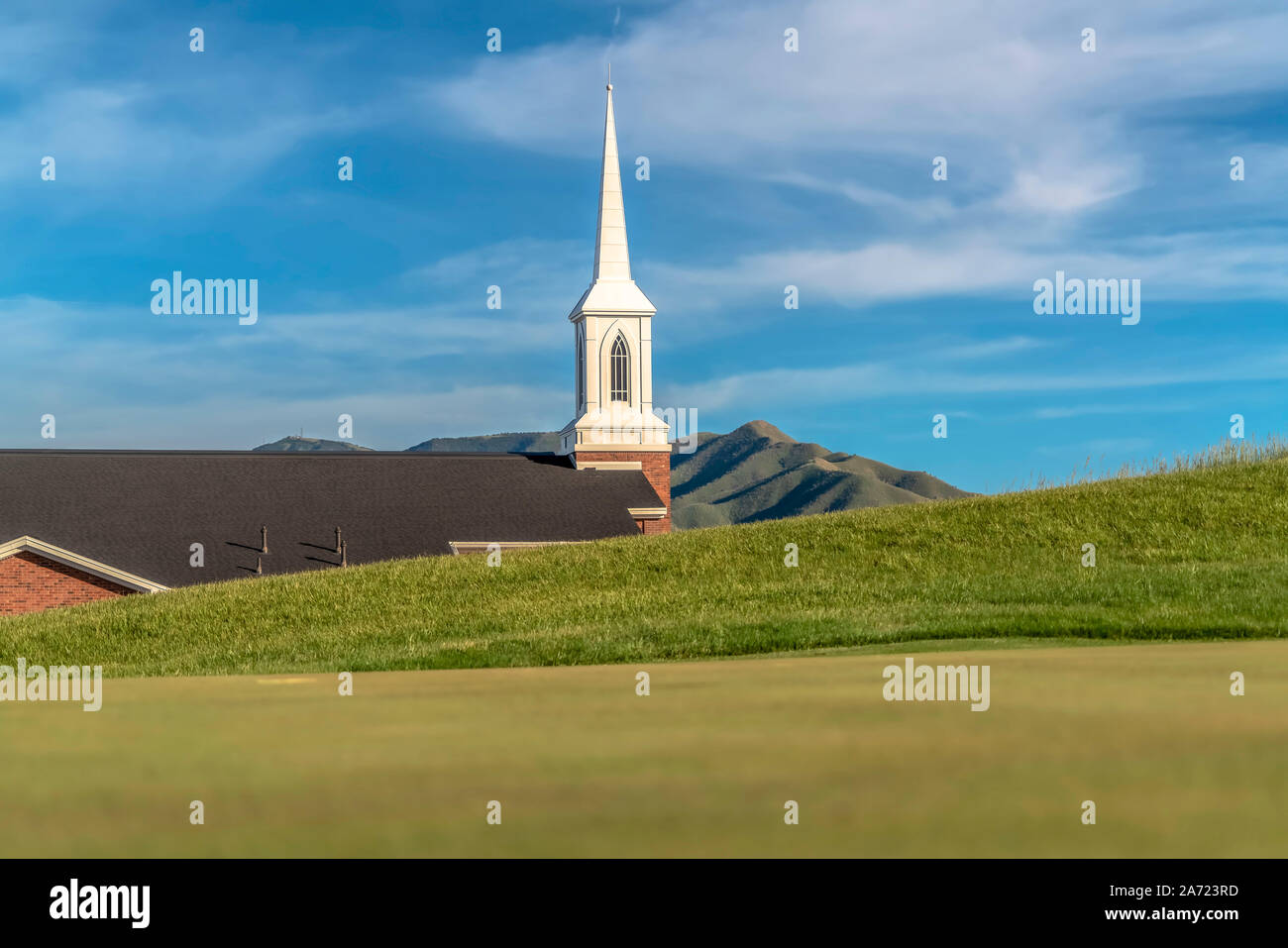 Roof and steeple of a church viewed from a golf course against cloudy ...
