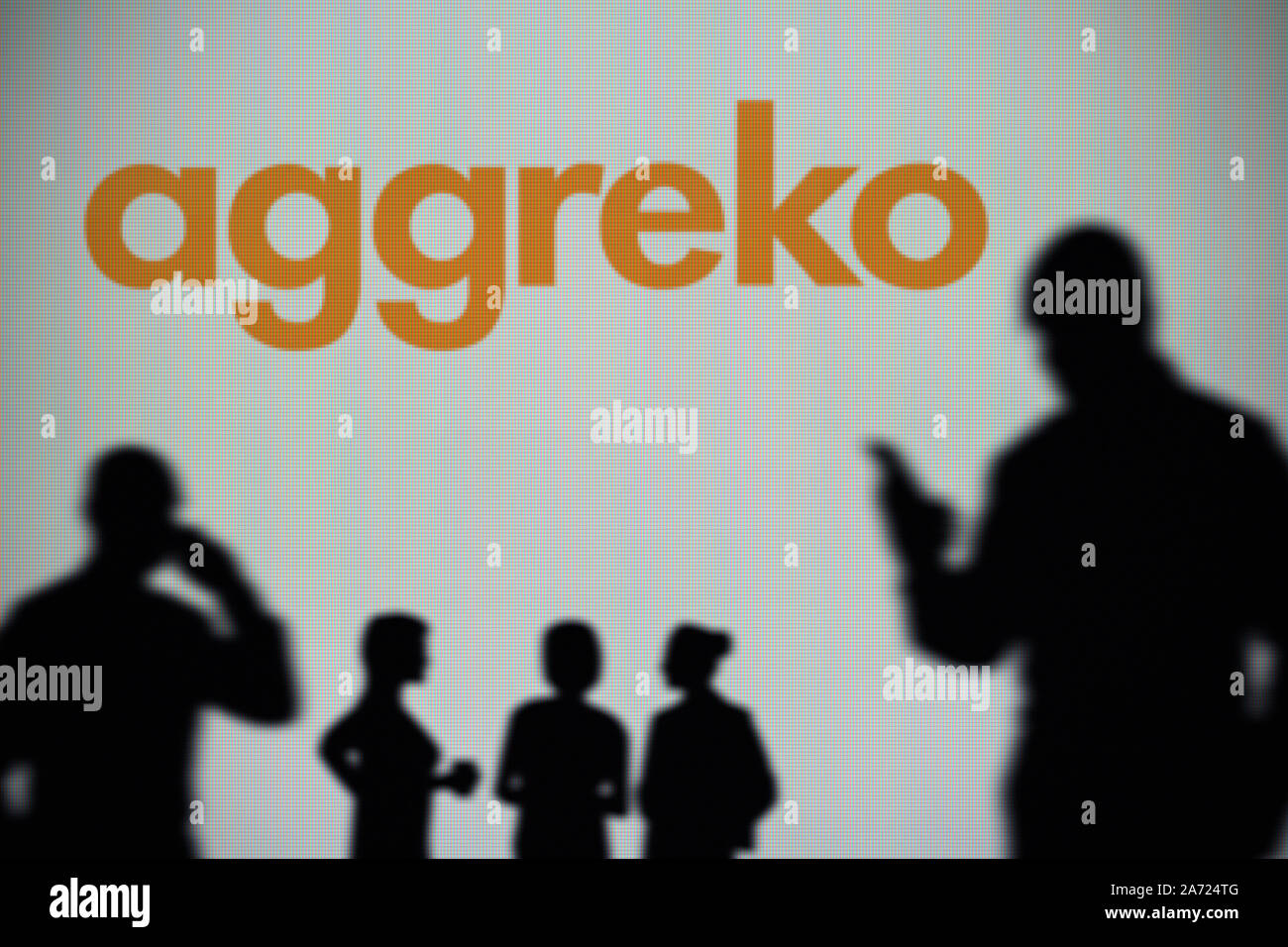 The Aggreko logo is seen on an LED screen in the background while a silhouetted person uses a ...