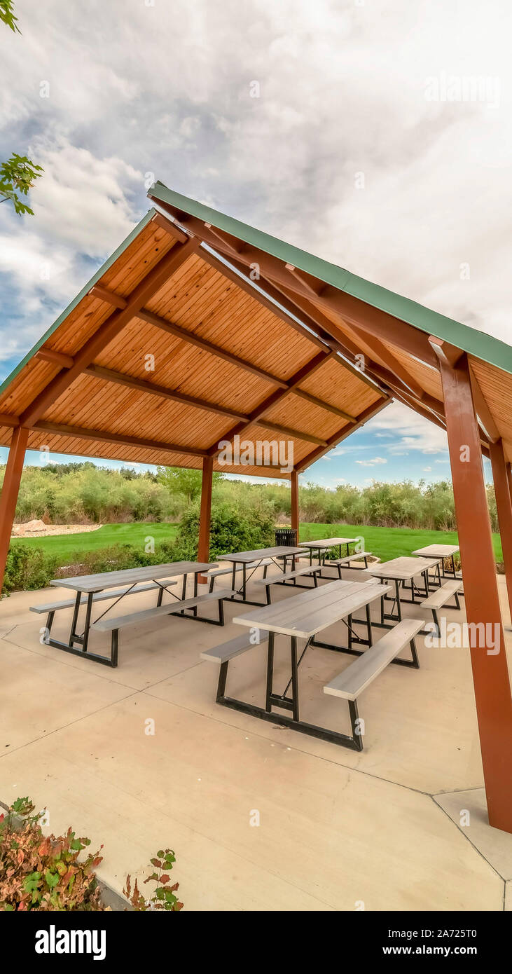Vertical A small picnic pavilion at a park with view of lush foliage ...