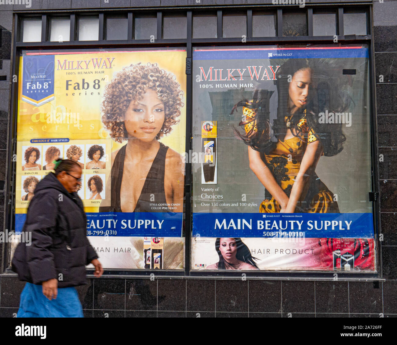 Woman walking along the street in Worcester, MA in front of large store ...