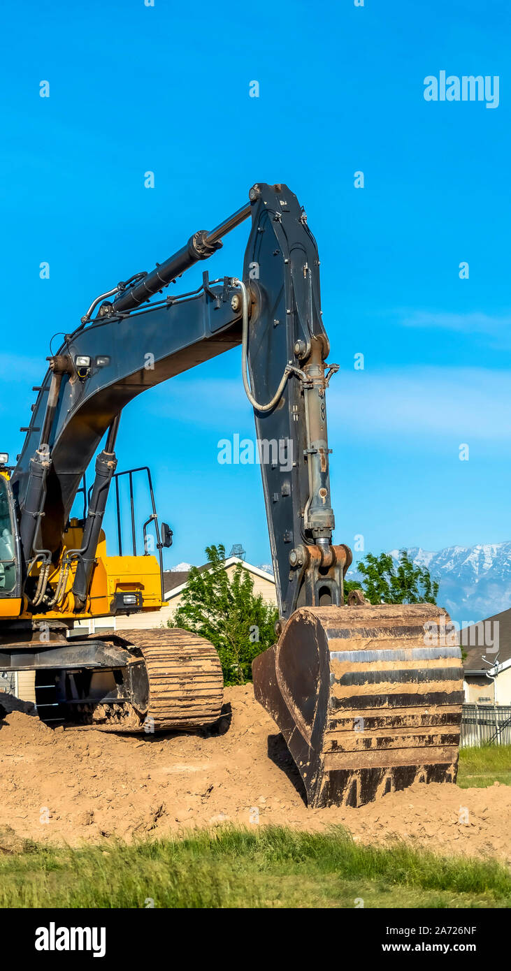 Vertical Close up of an excavator with arm bucket and continuous tracks ...