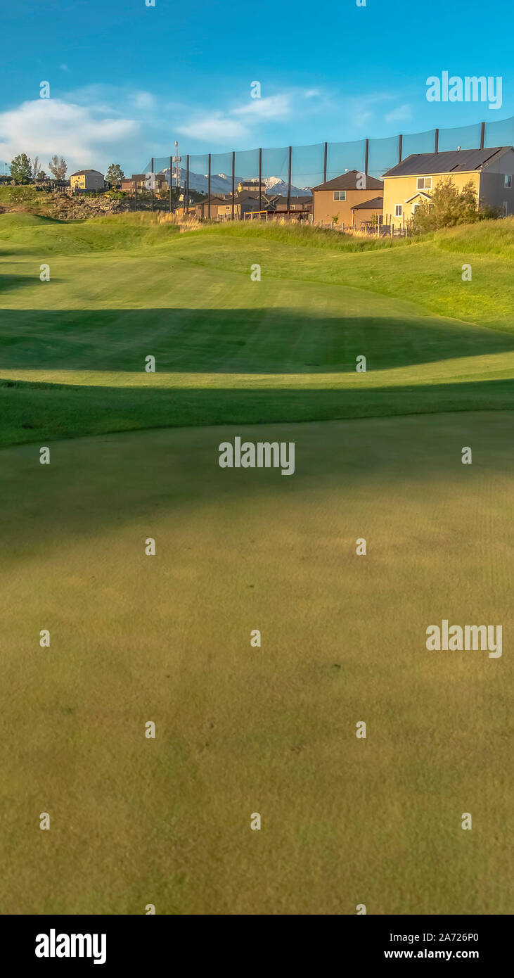 Vertical Scenic view of houses around a golf course under blue sky on a ...