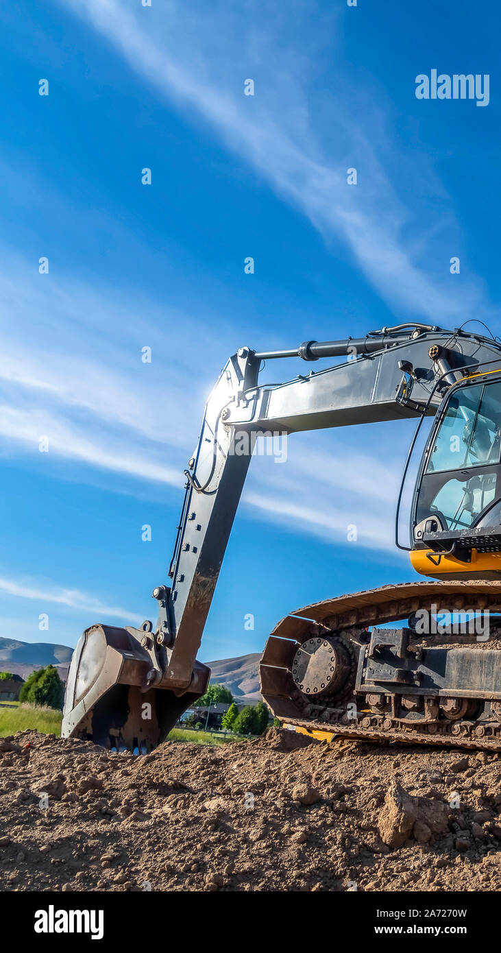 Vertical Yellow excavator with continuous tracks digging soil at a ...