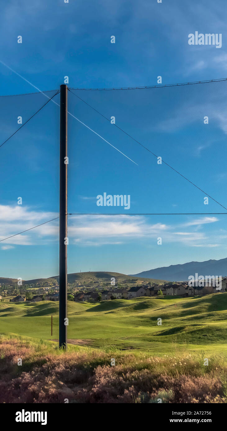 Vertical frame Fence with golf course homes and mountain against blue ...