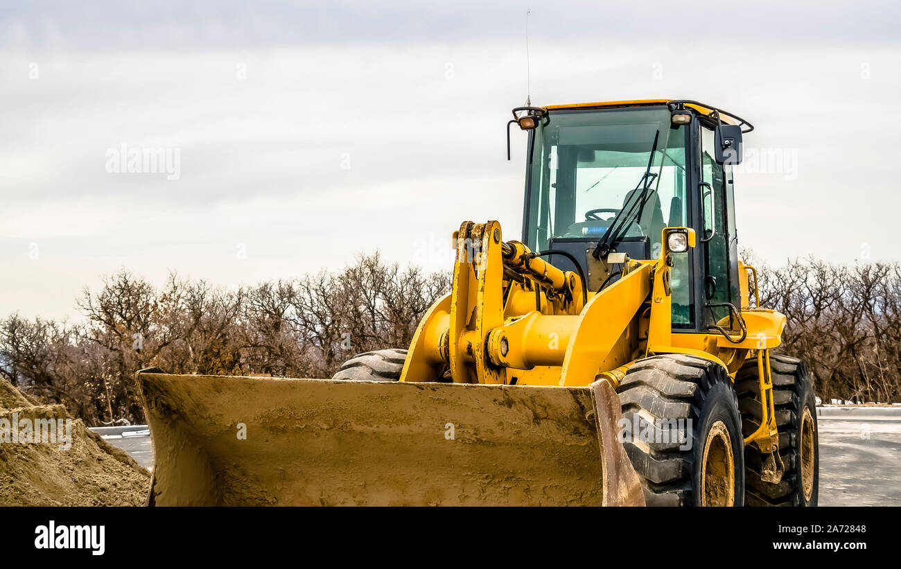 Panorama Focus on a yellow bulldozer with dirty bucket and wheels at a ...