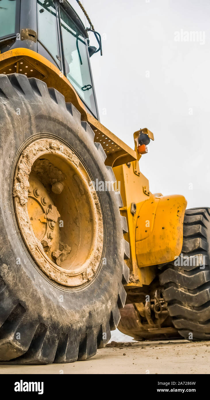 Vertical Focus on the black rubber wheels of a yellow bulldozer at a ...