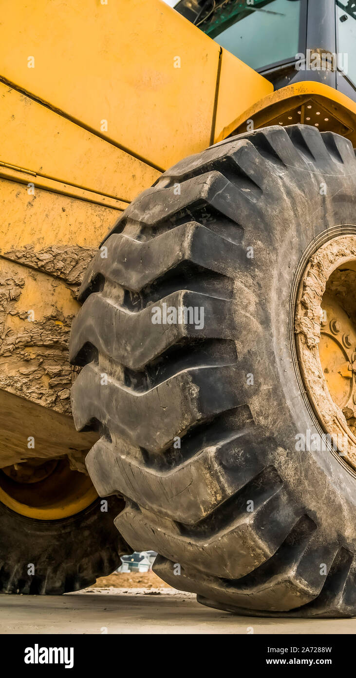 Vertical Focus on the black rubber wheels of a yellow bulldozer at a ...
