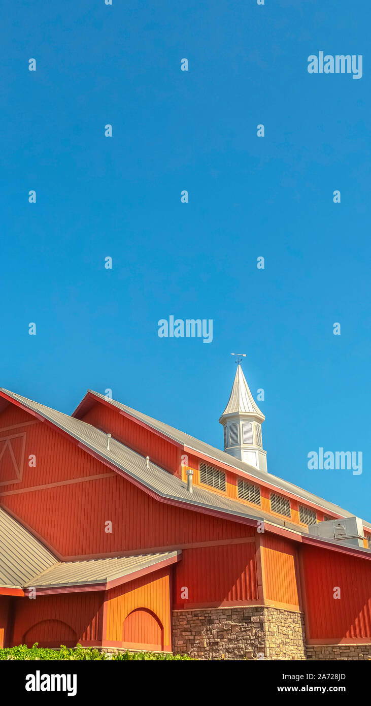 Vertical Colorful orange barn at a vinyard with clear blue sky ...