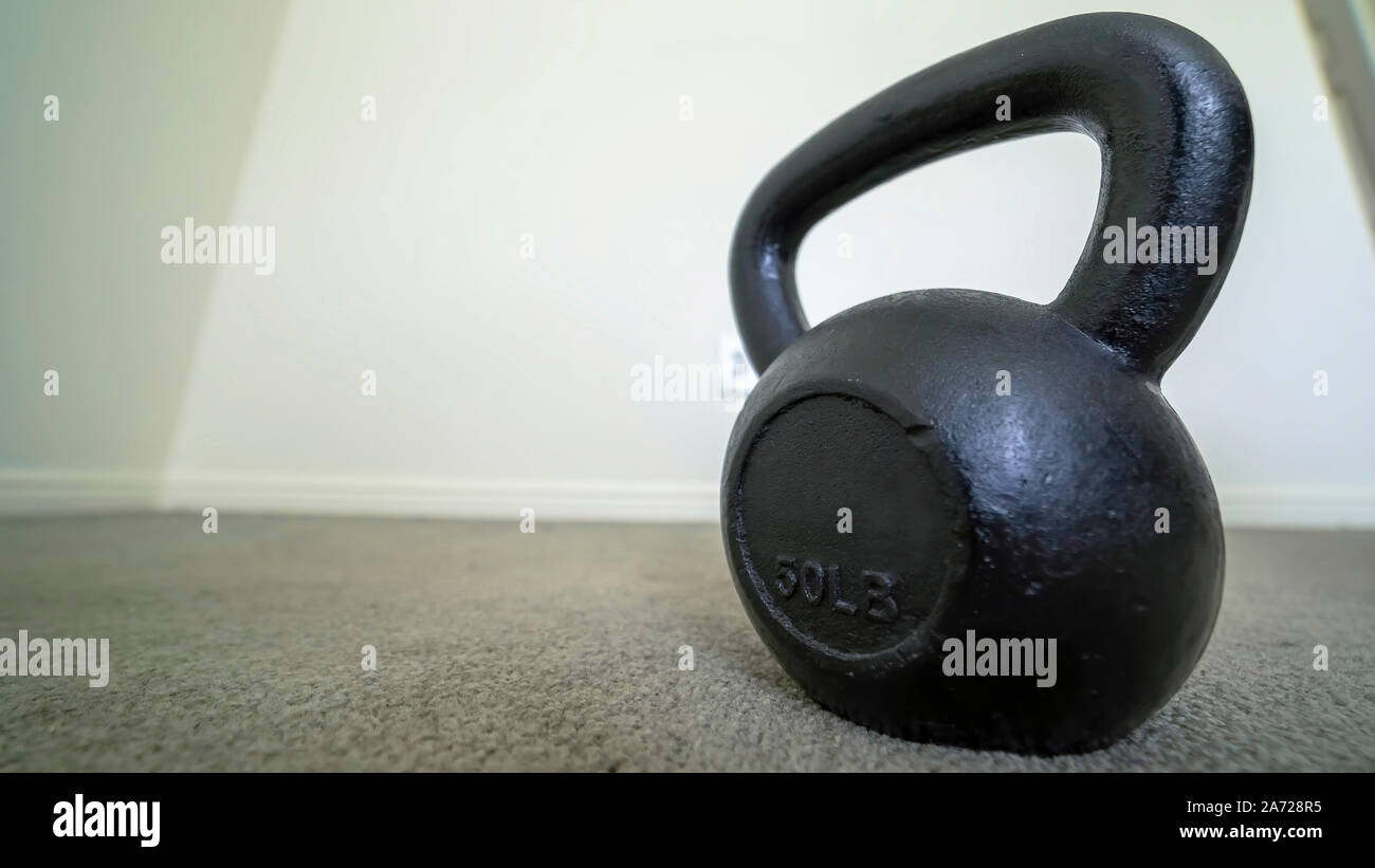 Panorama frame Focus on a heavy kettlebell inside a room with carpeted ...