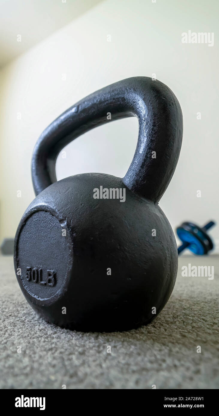Vertical Close up of black kettlebell inside a gym room with carpet ...