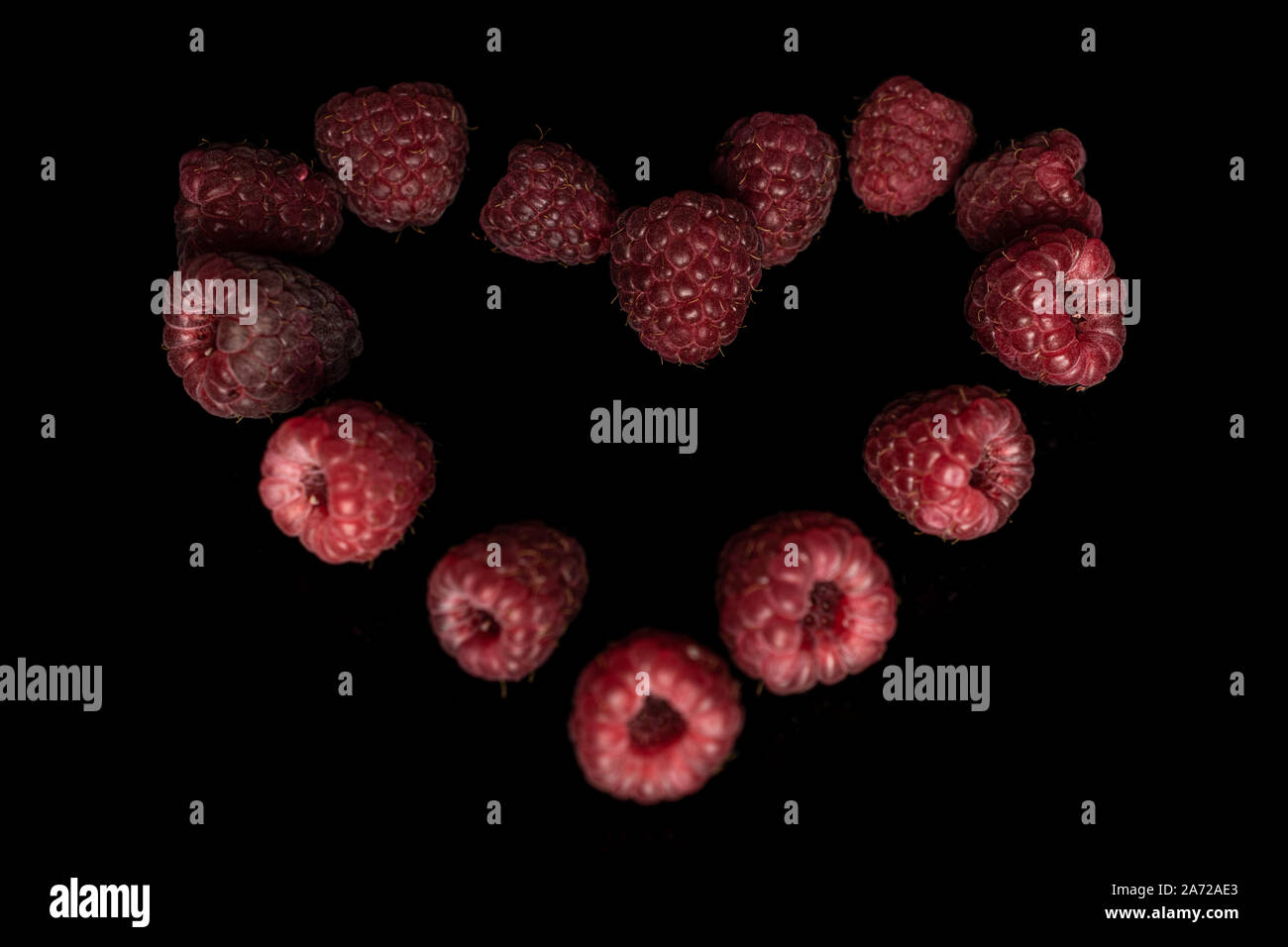 Lot of whole fresh crimson raspberry isolated on black glass Stock ...