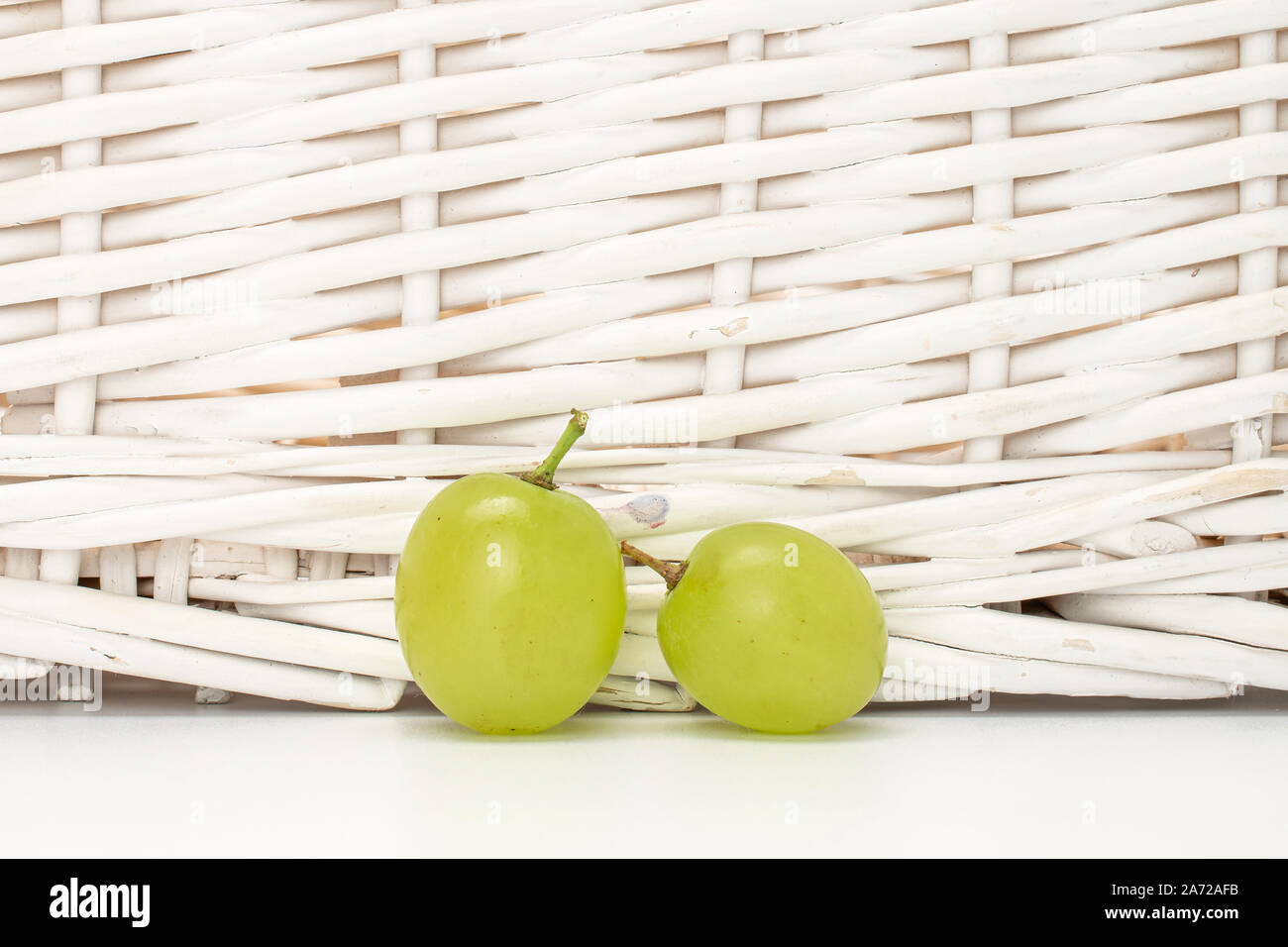Group of two whole green table grapes with braided wall behind isolated ...