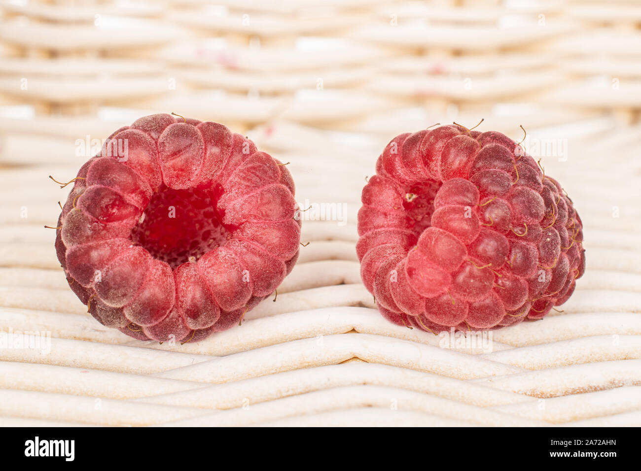 Group of two whole fresh crimson raspberry with braided rattan behind ...