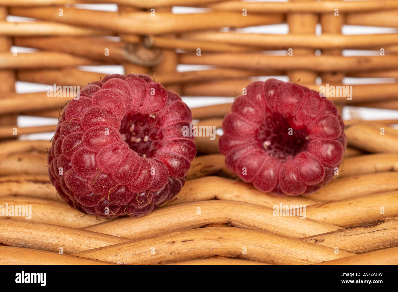 Group of two whole fresh crimson raspberry with braided rattan behind ...
