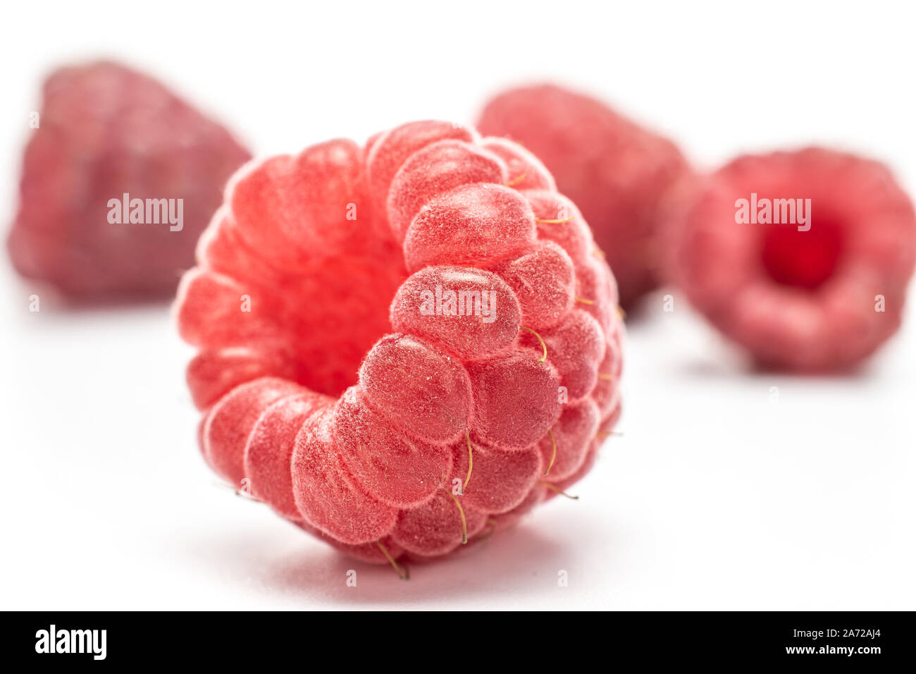 Group of four whole fresh crimson raspberry isolated on white ...