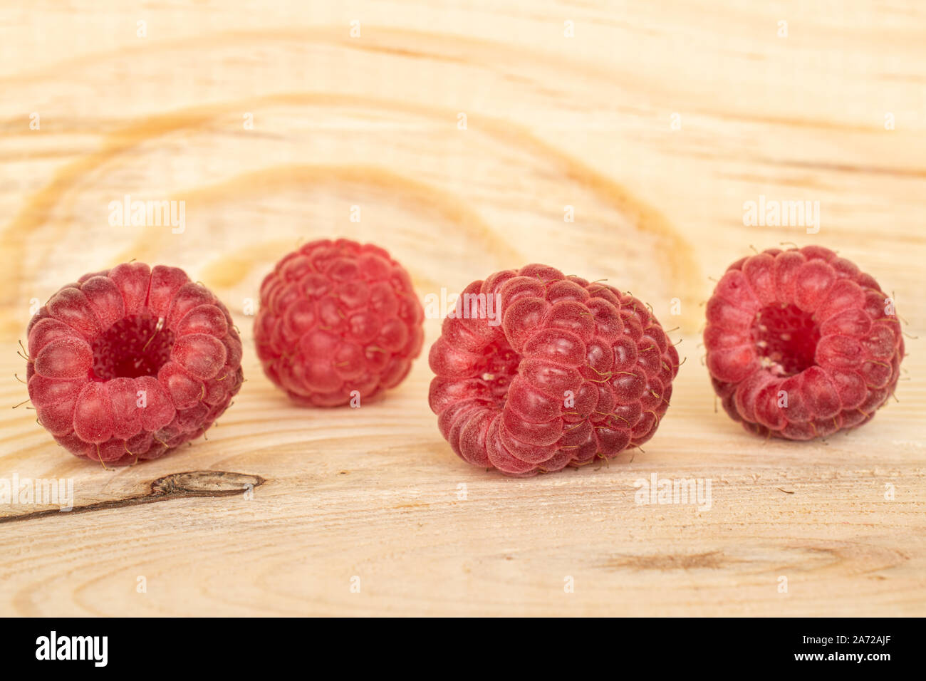 Group of four whole fresh crimson raspberry on natural wood Stock Photo ...