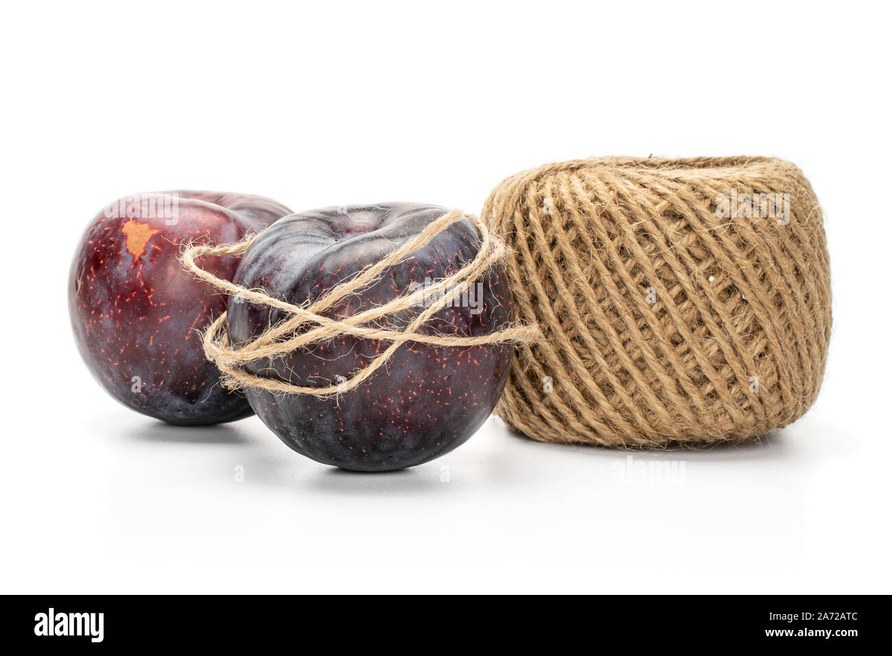 Group of two whole fresh red plum with spool tied by jute thread ...