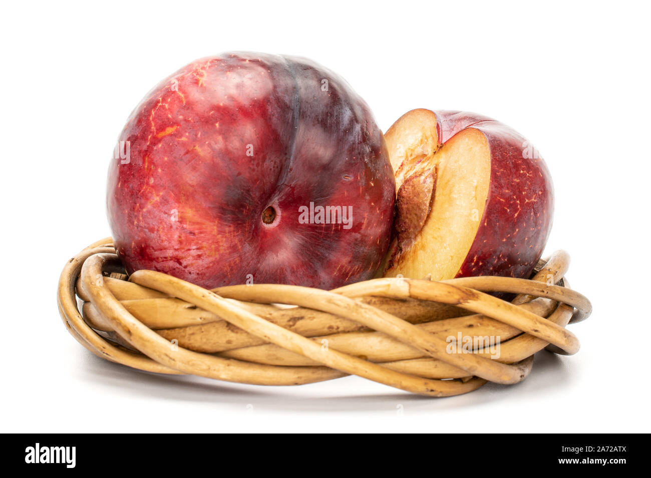 Group of one whole one half of fresh red plum in wiker nest isolated on ...