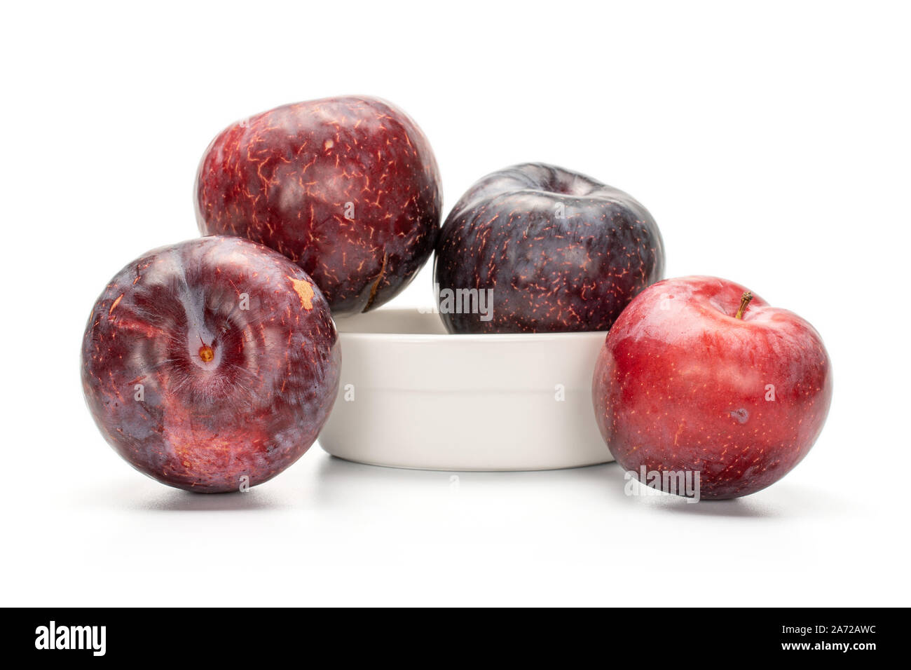 Group of four whole fresh red plum in ceramic stewpan isolated on white ...