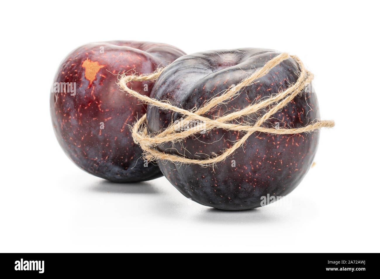 Group of two whole fresh red plum tied by jute thread isolated on white ...