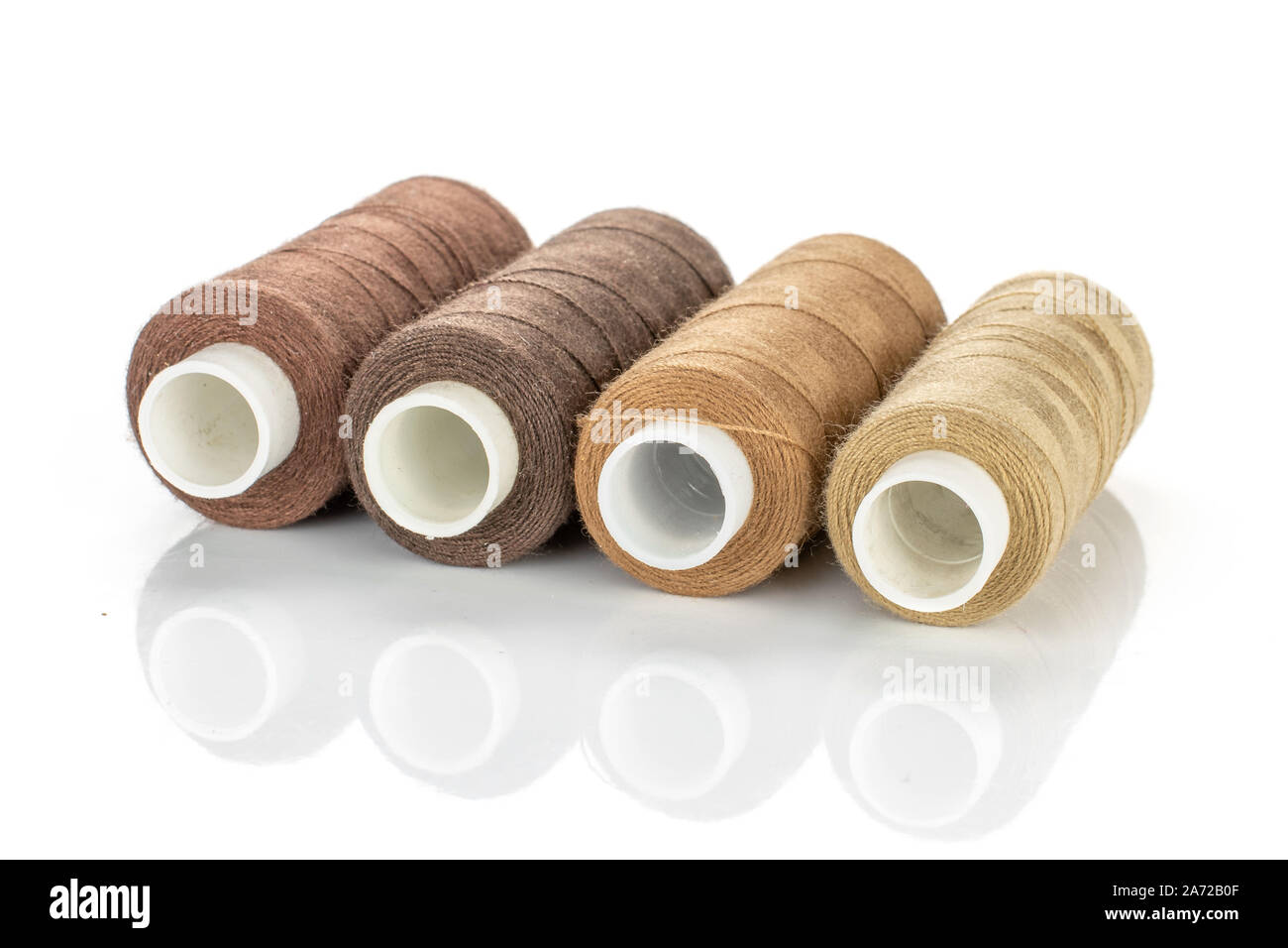 Group of four whole haberdashery item thread spools in row isolated on ...