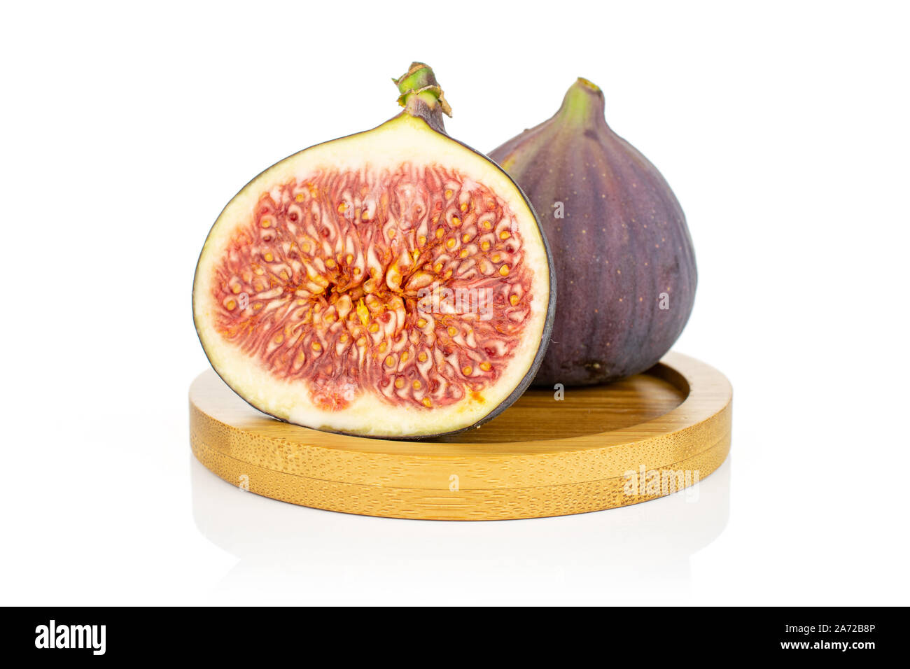 Group of one whole one half of fresh purple fig on bamboo coaster ...