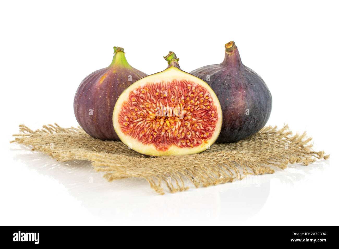 Group of two whole one half of fresh purple fig on natural sackcloth ...
