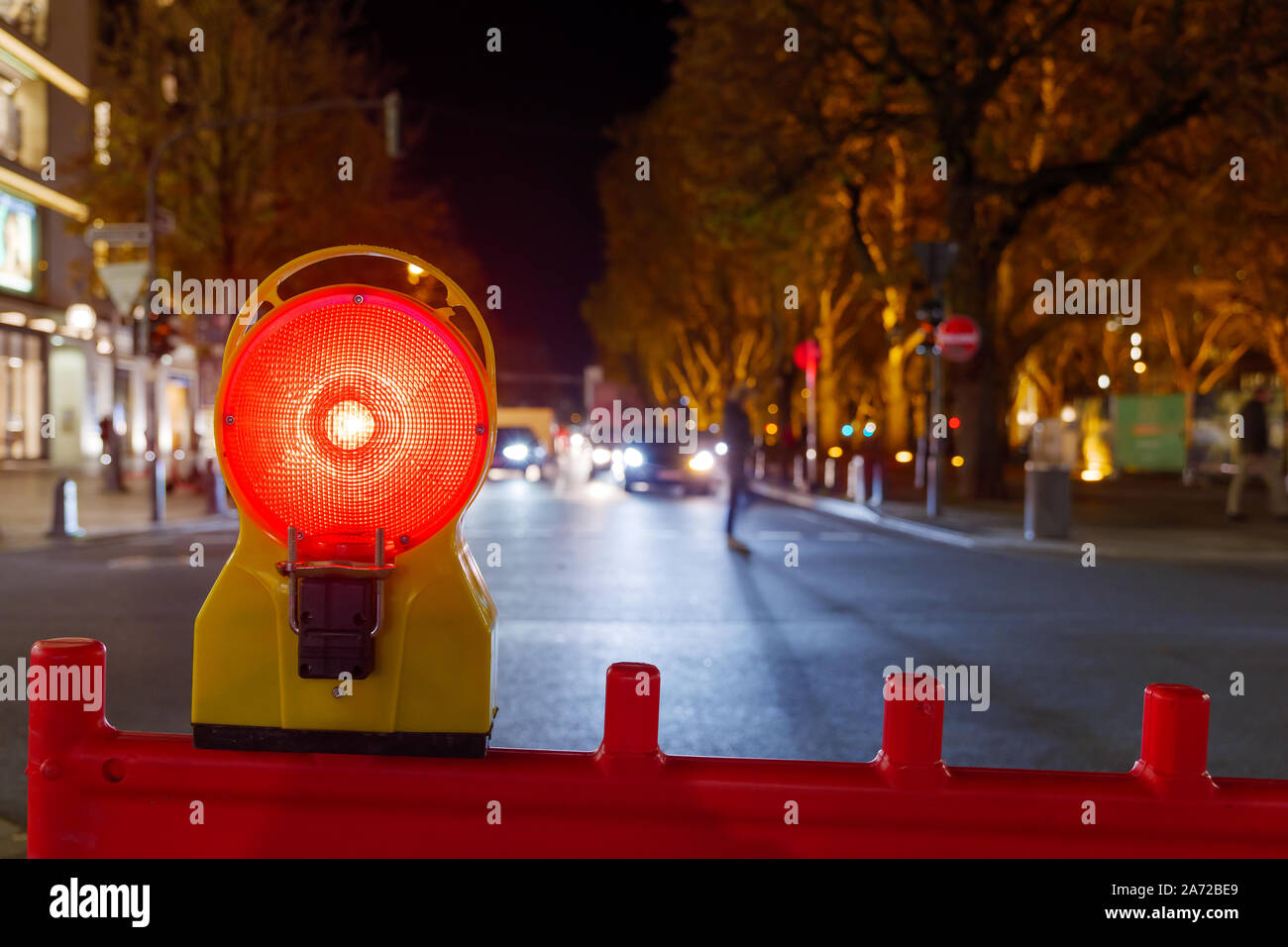 Night and close up view at red caution light and plastic barriers to ...