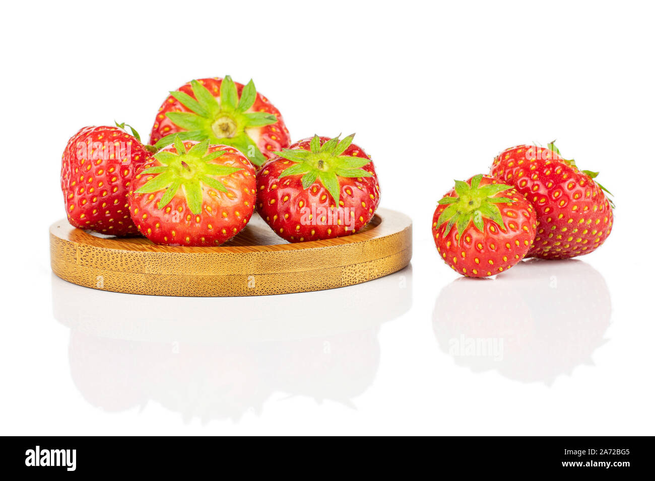 Group of six whole fresh red strawberry on bamboo coaster isolated on ...